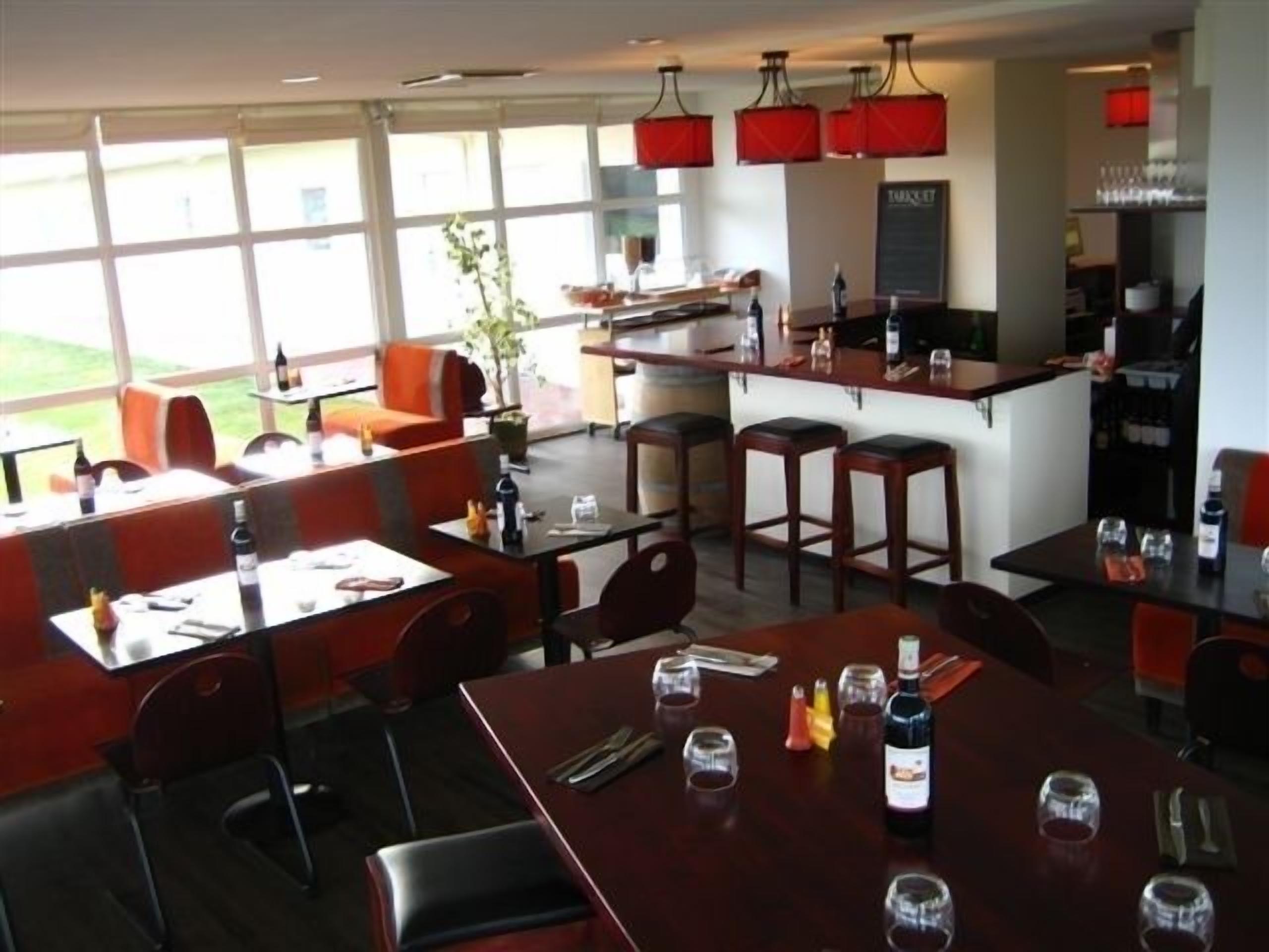 Restaurante com área de bar, assentos e vista para o exterior.