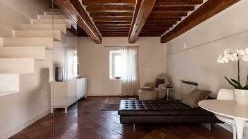 Um interior moderno com escada, sofá, mesa pequena e uma orquídea em vaso.