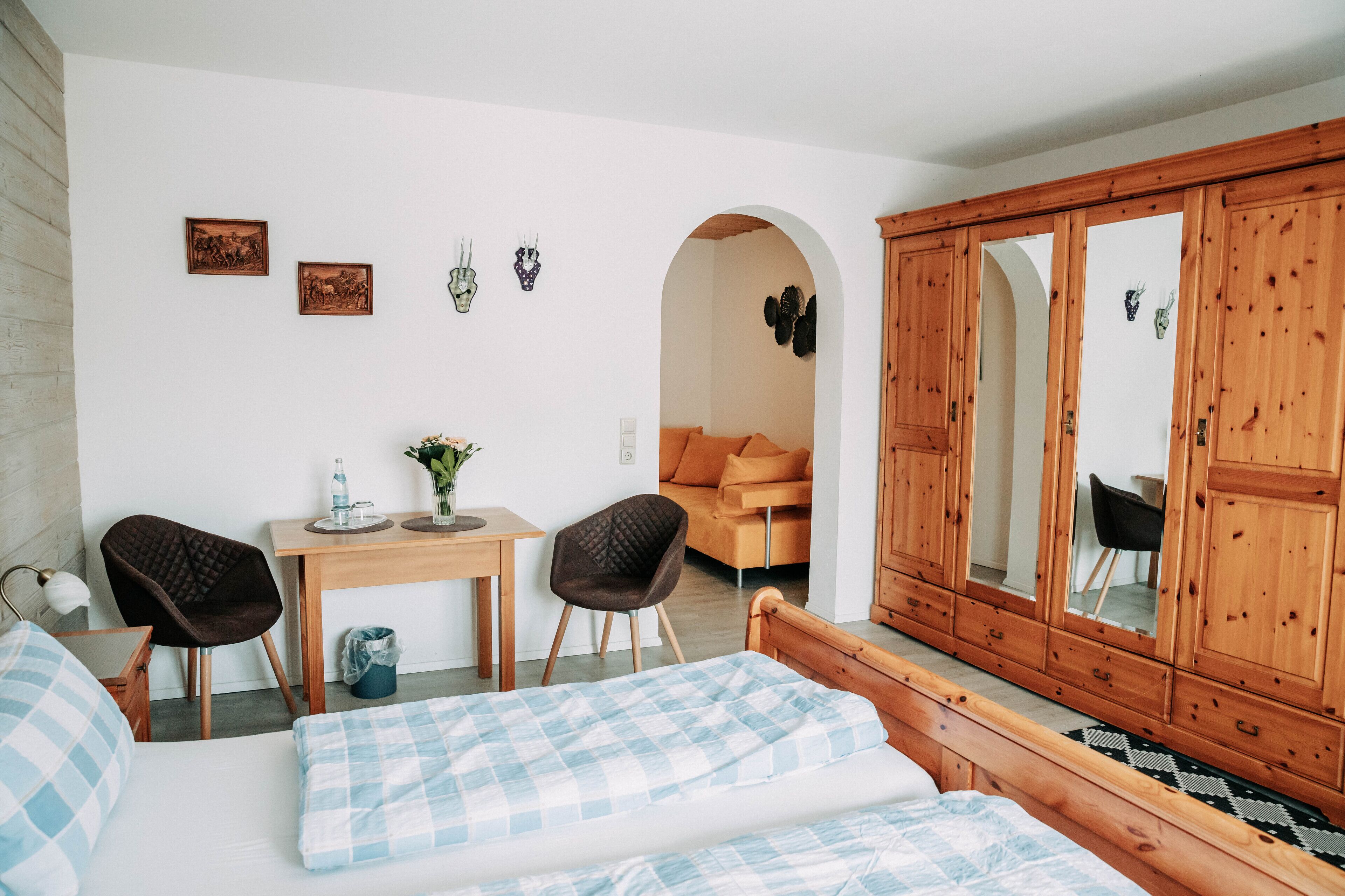 Quarto com cama, escrivaninha, duas cadeiras, guarda-roupa e espelho.
