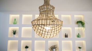 Um interior moderno com um lustre central e várias prateleiras iluminadas na parede.
