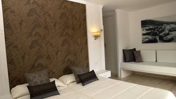 Quarto com cama grande, sofá e luminária na parede.