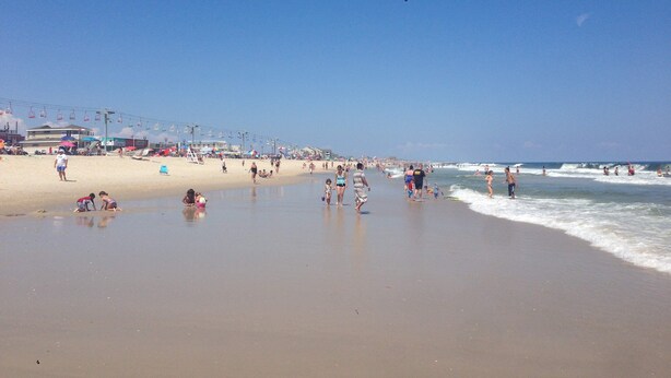 Uma praia com pessoas, guarda-sóis e uma torre de salva-vidas.