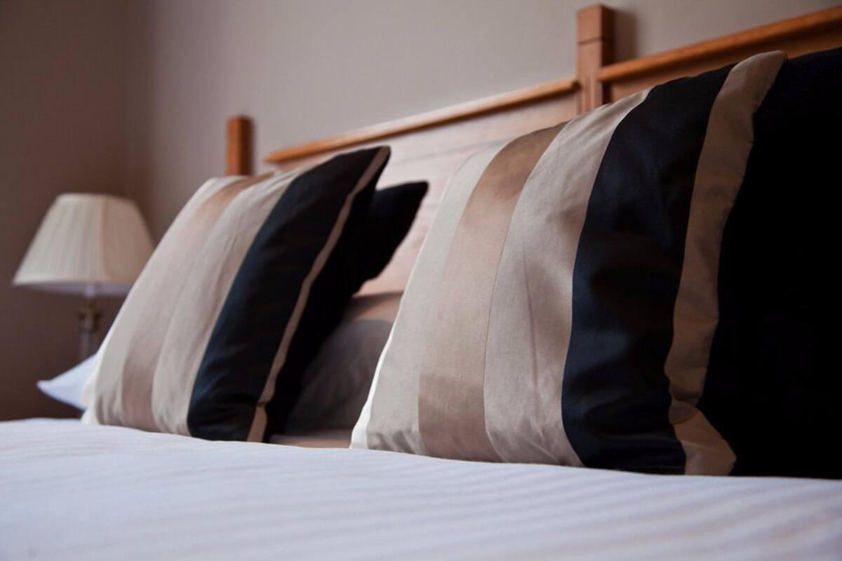 Uma cama com várias almofadas e cabeceira de madeira.