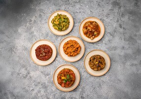 Seis pratos de comida dispostos sobre uma superfície texturizada.