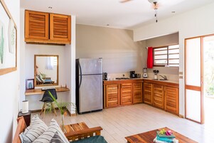 Uma cozinha compacta com armários de madeira, geladeira e um espaço de refeições com banco e mesa.