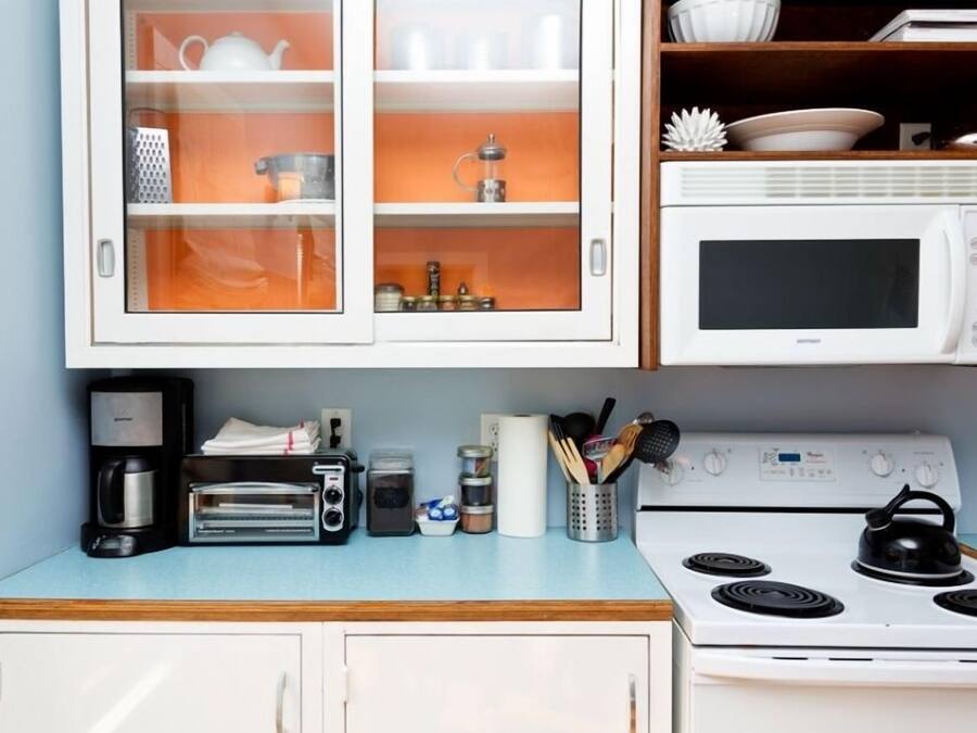 Uma cozinha com fogão branco, micro-ondas e armário com portas de vidro.