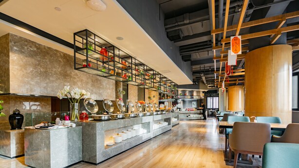 Um restaurante moderno com um balcão extenso, prateleiras com louças e áreas de estar.