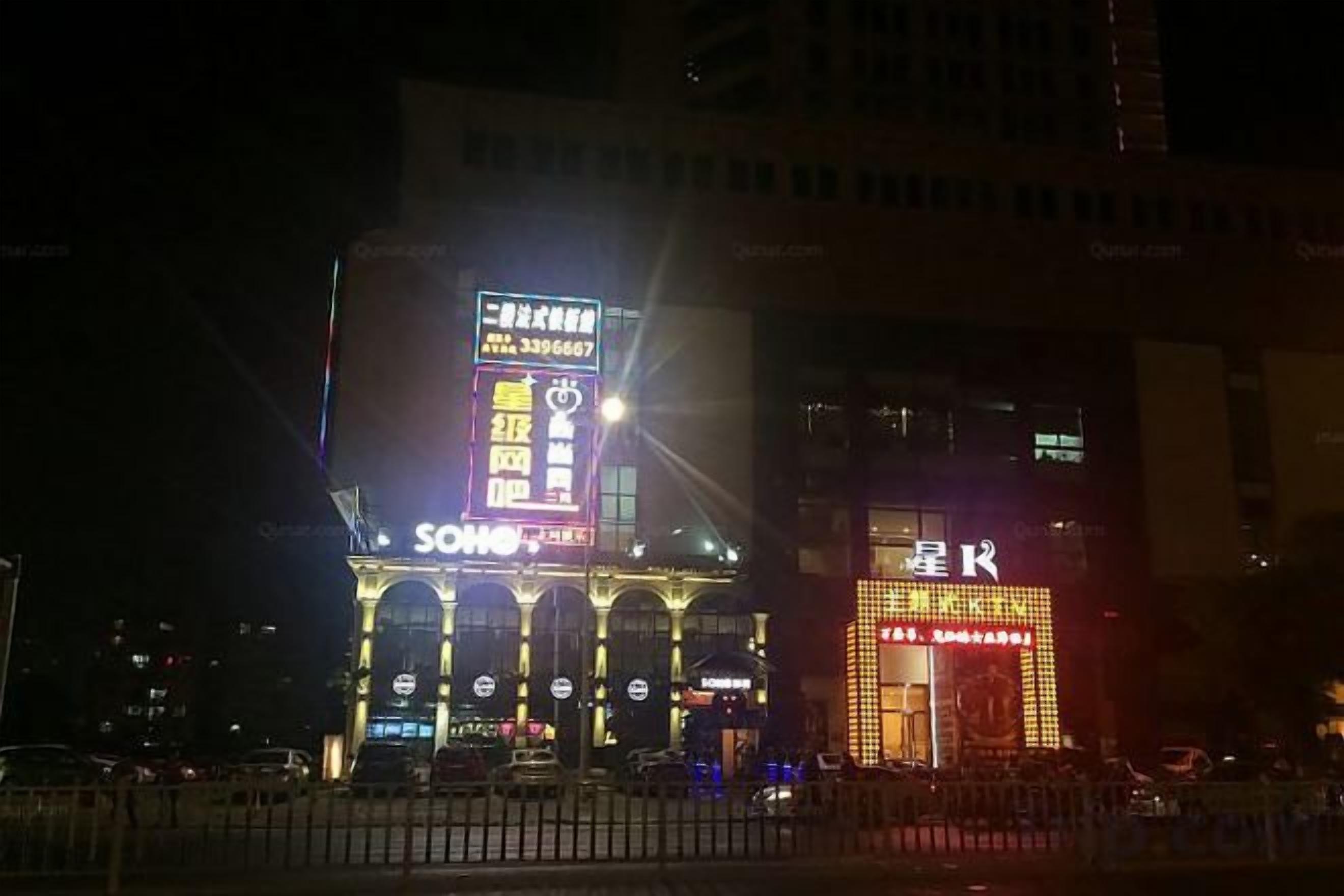 Um edifício com sinalização iluminada, incluindo um destaque para o letreiro 'SONO' e um letreiro 'STAR' com esquema de cores vermelho e amarelo.