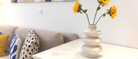 Uma sala de estar moderna com uma mesa branca, um sofá cinza e um quadro na parede.