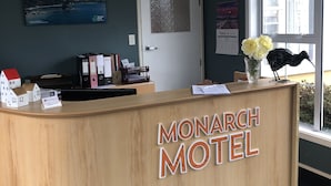 Balcão de recepção do Monarch Motel com vista para o exterior através de uma grande janela.