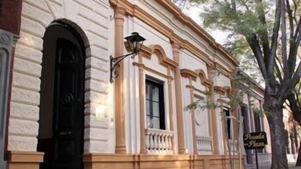 Um edifício com estilo arquitetônico clássico, destacando uma porta em arco e uma varanda com corrimão.
