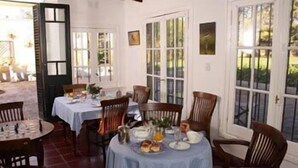 Uma área de refeições com mesas e cadeiras redondas, cobertas por toalhas azuis.