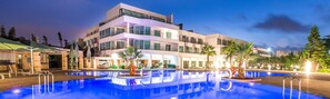 Um hotel moderno com uma grande piscina ao ar livre, várias varandas e paisagismo exuberante.