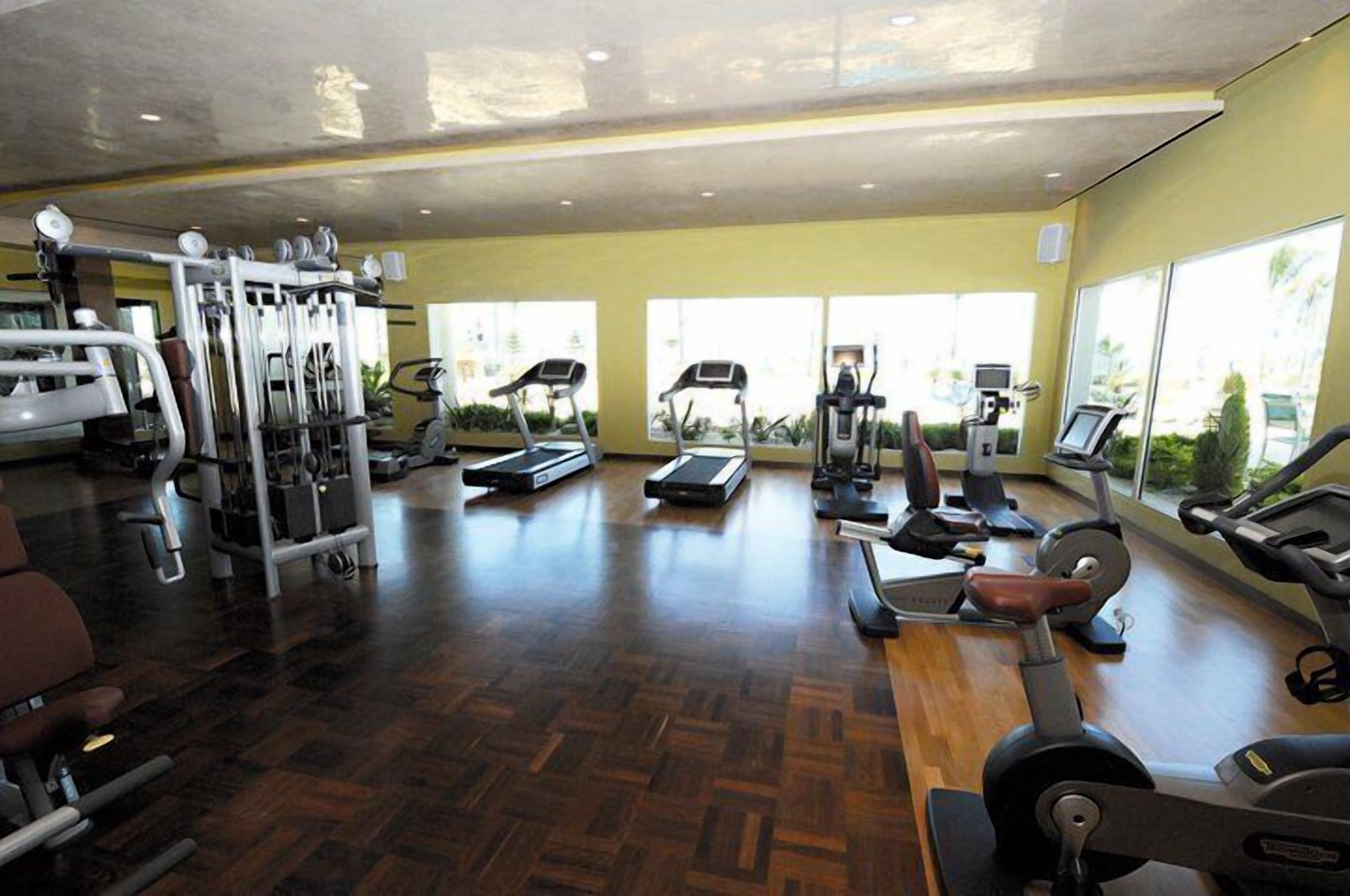Uma academia com esteiras, elípticos e equipamentos de musculação.