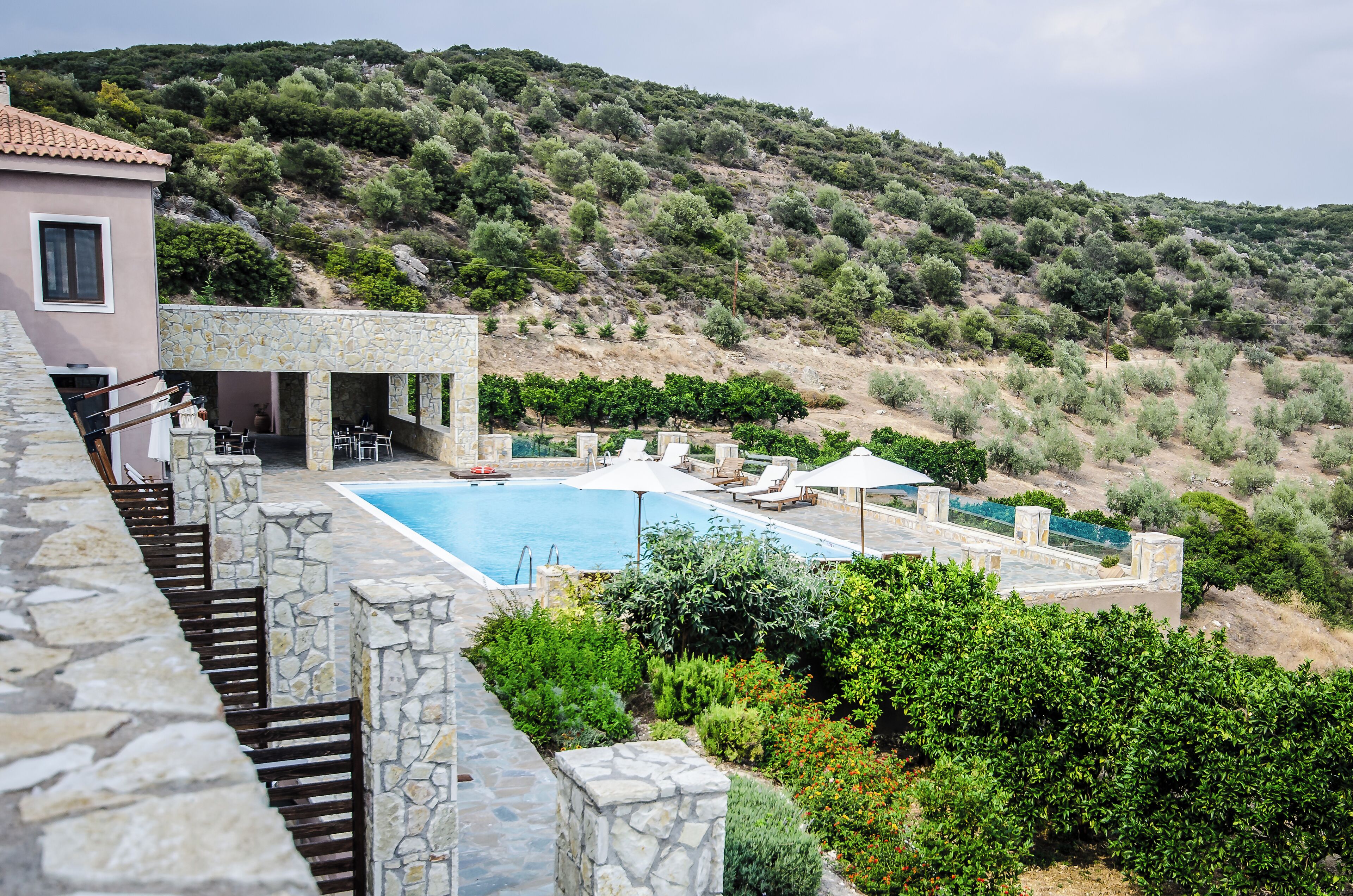 Uma área de piscina com paredes de pedra, espreguiçadeiras e guarda-sóis.