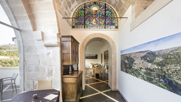 Uma área de refeições com vista para a paisagem urbana através de uma janela em arco.