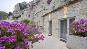 Um edifício de pedra com varanda, janelas amplas e uma parede de pedra adornada com flores.