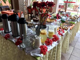 Mesa de buffet com diversos alimentos, bebidas e um espaço para café.
