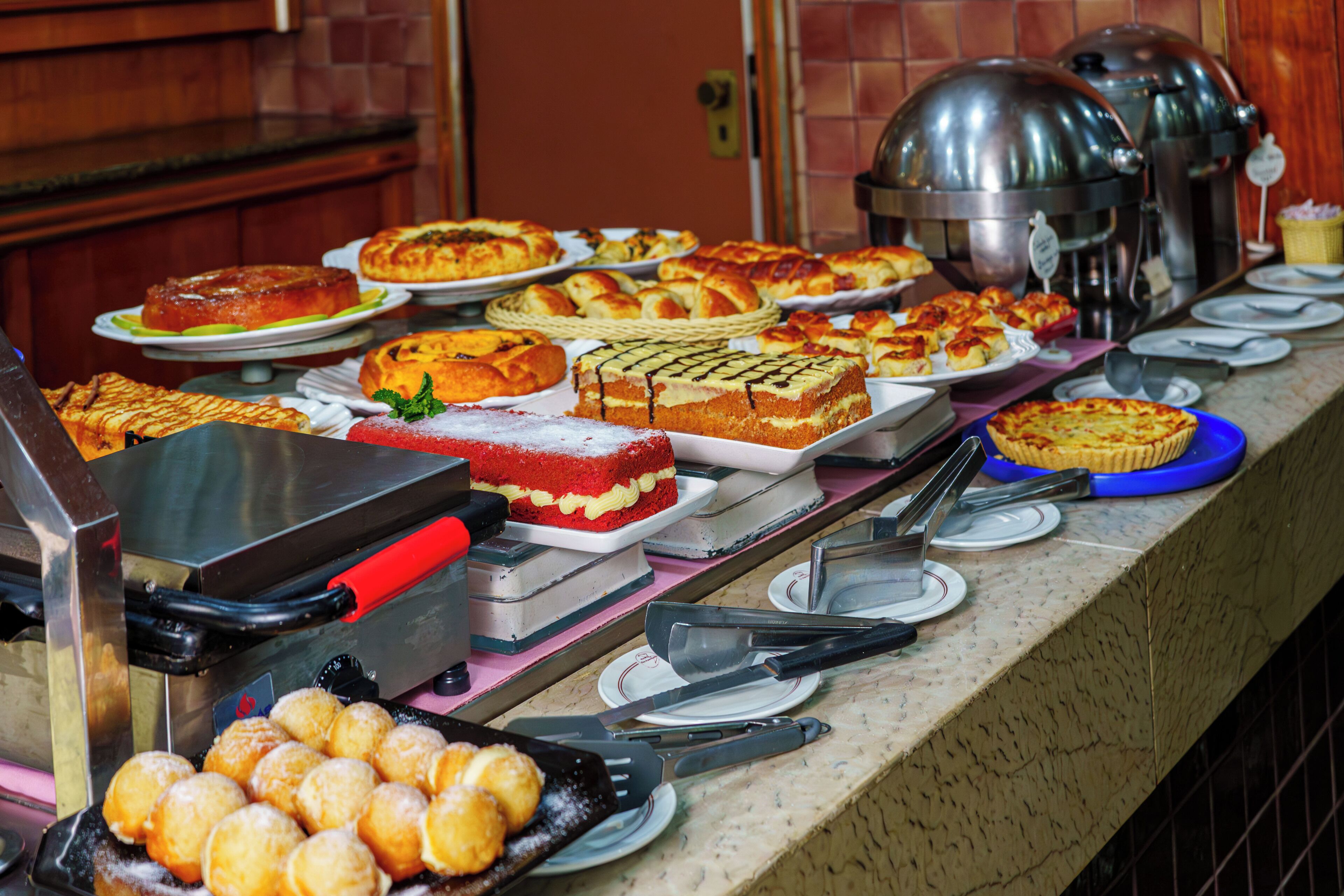 Um buffet com diversos produtos de panificação e pastelaria.