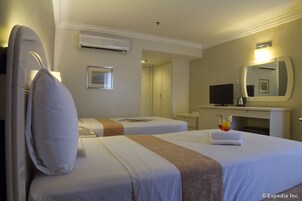 Quarto de hotel com duas camas, uma escrivaninha, uma televisão e um espelho.