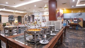 Disposição de buffet com várias estações de serviço, balcão de madeira e piso de mármore.