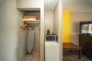 Quarto compacto com cama, micro-ondas, mini-geladeira e televisão.