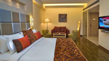 Quarto de hotel com uma cama grande, televisão, escrivaninha e uma cadeira.