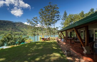 Uma propriedade à beira do lago com área de pátio, mobiliário de exterior e vista para o lago e colinas ao redor.