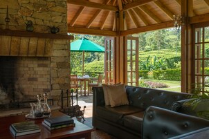 Um quarto acolhedor com lareira de pedra, um sofá de couro e vista para vegetação exuberante.