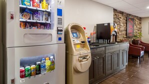Uma máquina de vendas com lanches e bebidas, uma máquina de café e a placa da Red Roof.