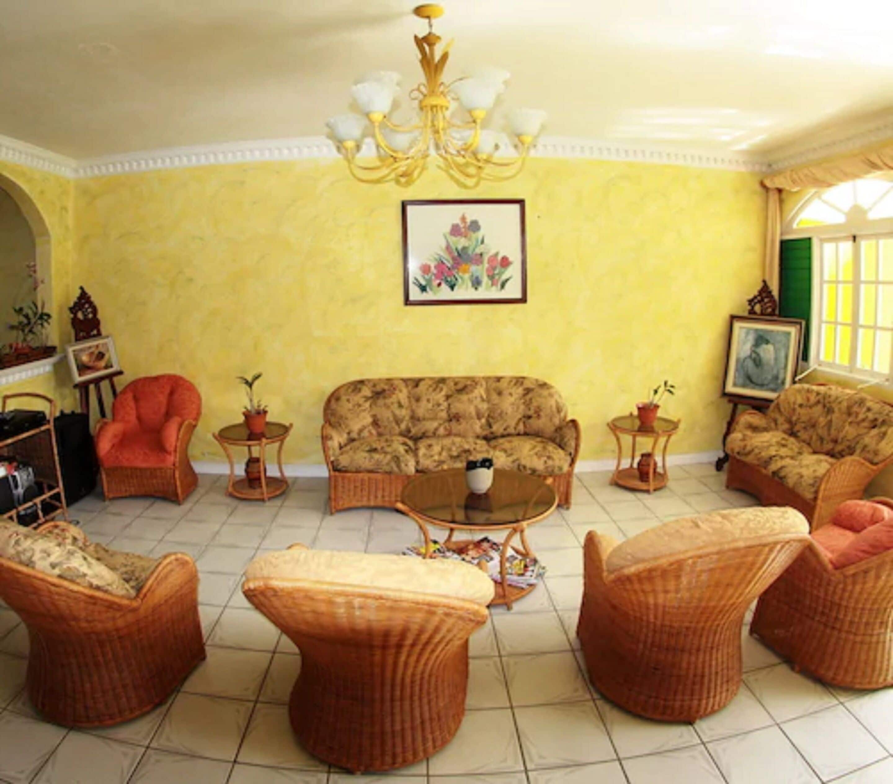 Uma sala de estar com sofá, poltronas, mesa de centro e lustre.