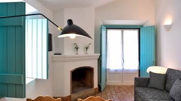 Uma sala de estar aconchegante com lareira, detalhes em tons de verde-água, um sofá e uma mesa com cadeiras.