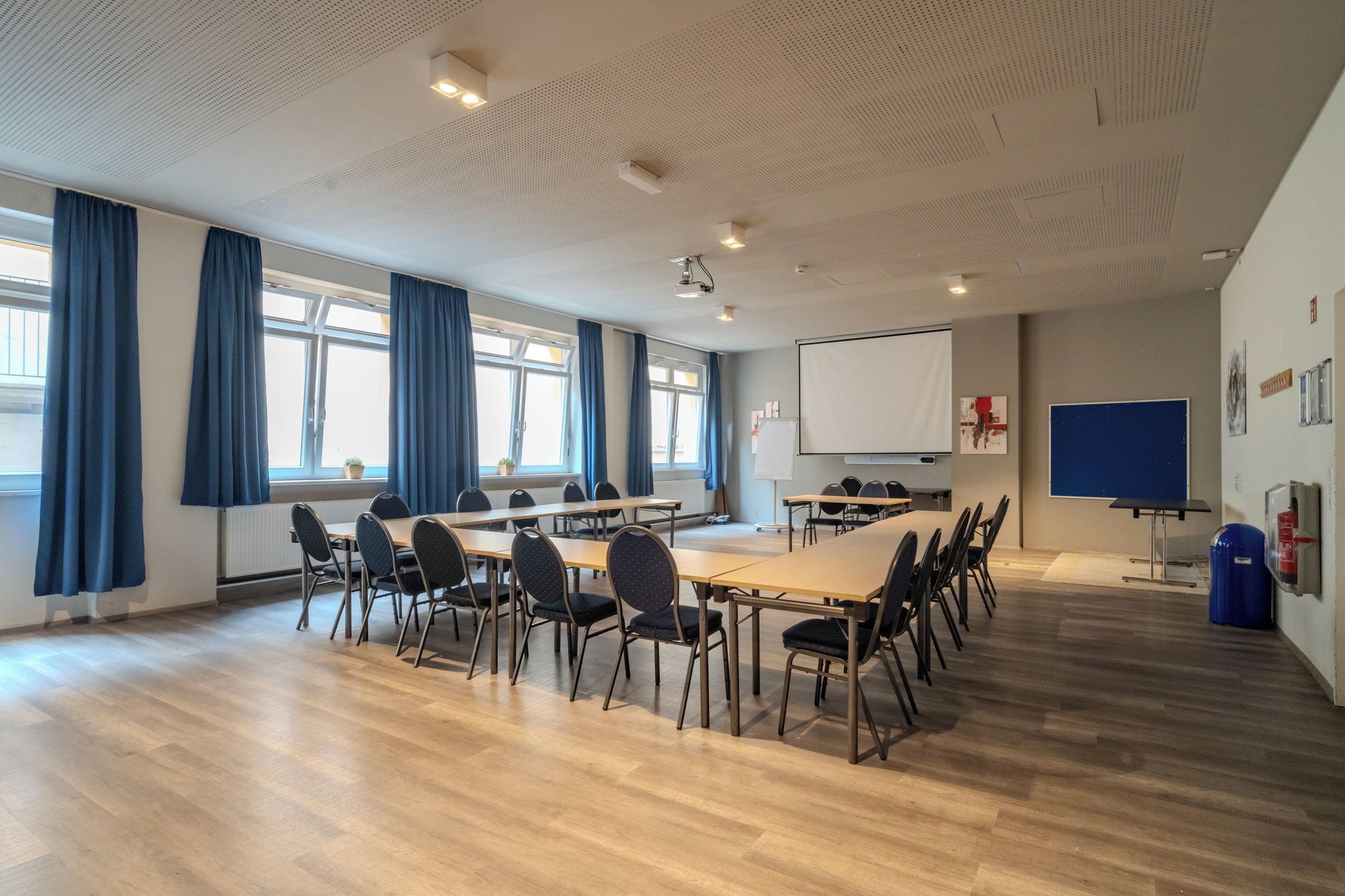 Uma sala de conferências com uma mesa comprida, cadeiras, um projetor e um quadro branco.