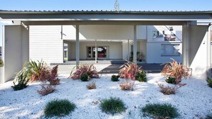 Espaço coberto ao ar livre com chão de cascalho e diversas plantas.