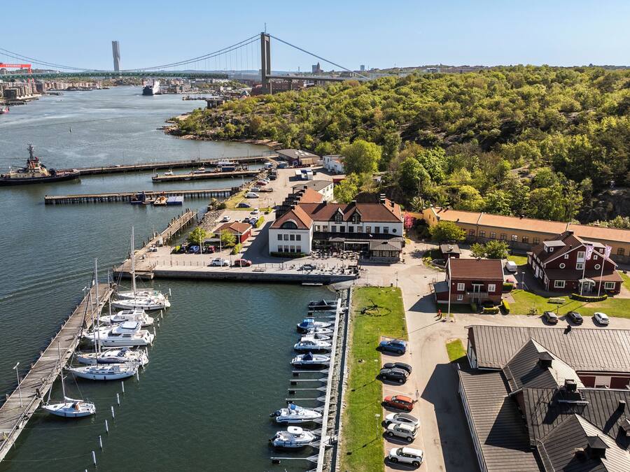 Uma marina com barcos atracados, uma ponte ao fundo e edifícios com telhados vermelhos.