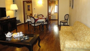 Sala de estar com sofá, mesa de centro, televisão e área de jantar com cadeiras e mesa posta para quatro pessoas.