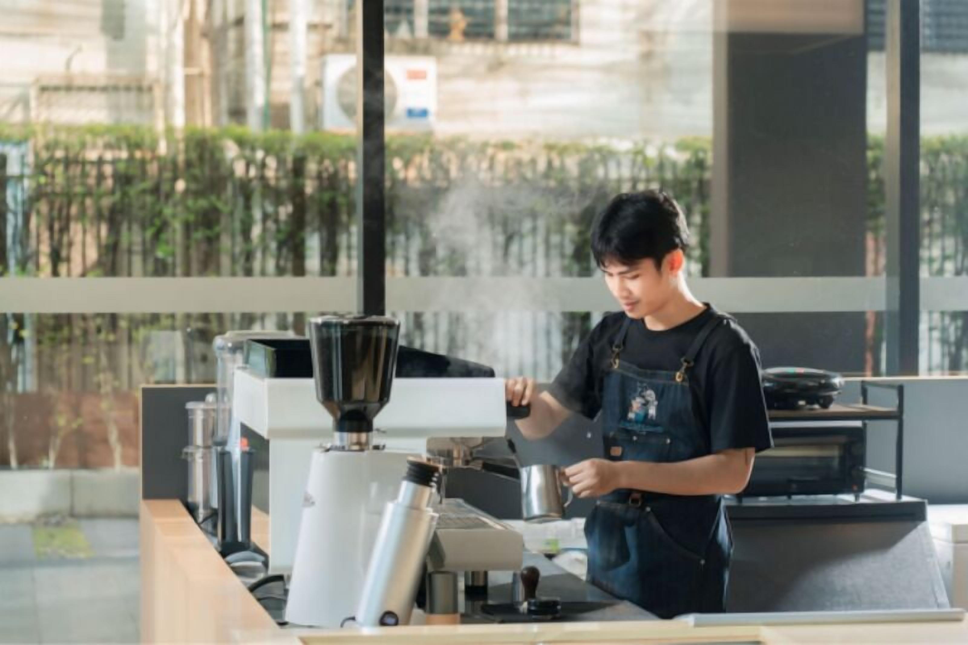 Uma pessoa preparando café em um balcão, com uma cafeteira e um moedor.
