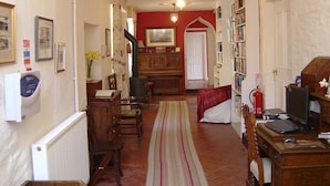 Uma sala de estar aconchegante com lareira, uma escrivaninha de madeira com um computador e uma estante repleta de livros.