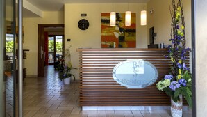 Um balcão de recepção com uma placa indicando "B&B Residence", um relógio e uma pintura abstrata moderna.