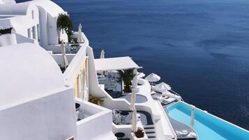 Um edifício branco com piscina e vista para o mar.