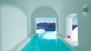 Uma piscina infinita moderna com vista clara para o mar e terra distante.