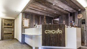 Um balcão de recepção com fundo de madeira e uma placa de neon com a inscrição "CRYCHAR".