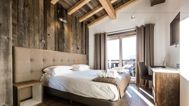 Quarto com cama grande, cabeceira de madeira e escrivaninha com cadeira.