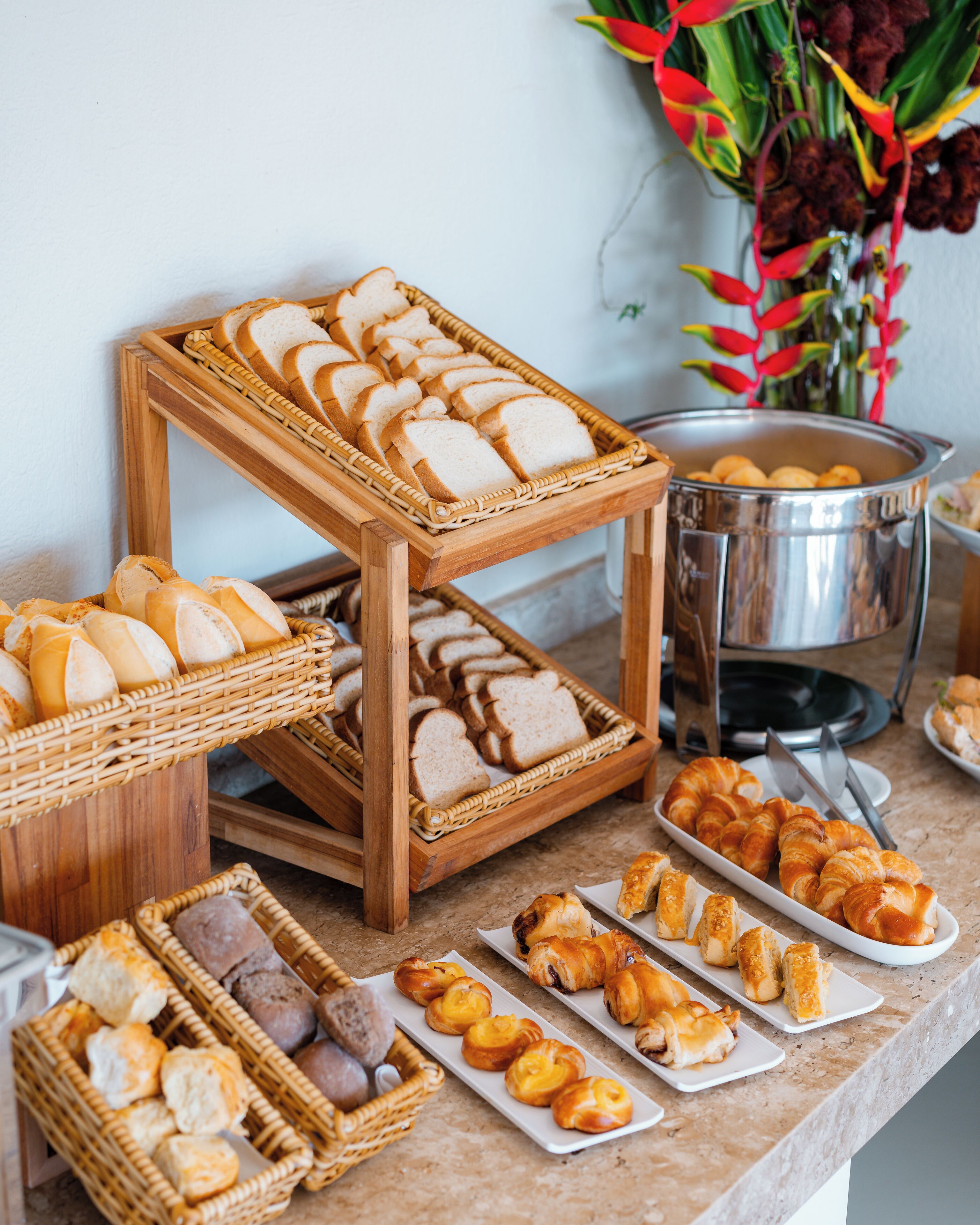 Buffet com diversos pães e doces à mostra.