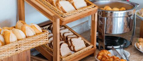 Buffet com diversos pães e doces à mostra.