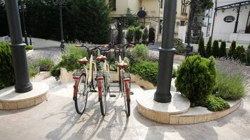 Uma área de estacionamento para bicicletas com um design circular, cercada por vegetação e um edifício ao fundo.