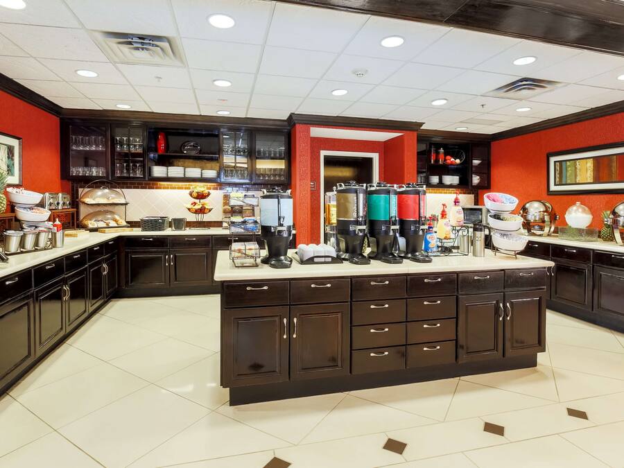 Cozinha moderna com armários escuros, uma ilha central e diversos eletrodomésticos.
