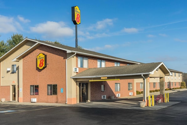 Um motel Super 8 com fachada de tijolos, entrada coberta e estacionamento.