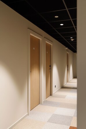Corredor com portas, piso ladrilhado e iluminação embutida no teto.
