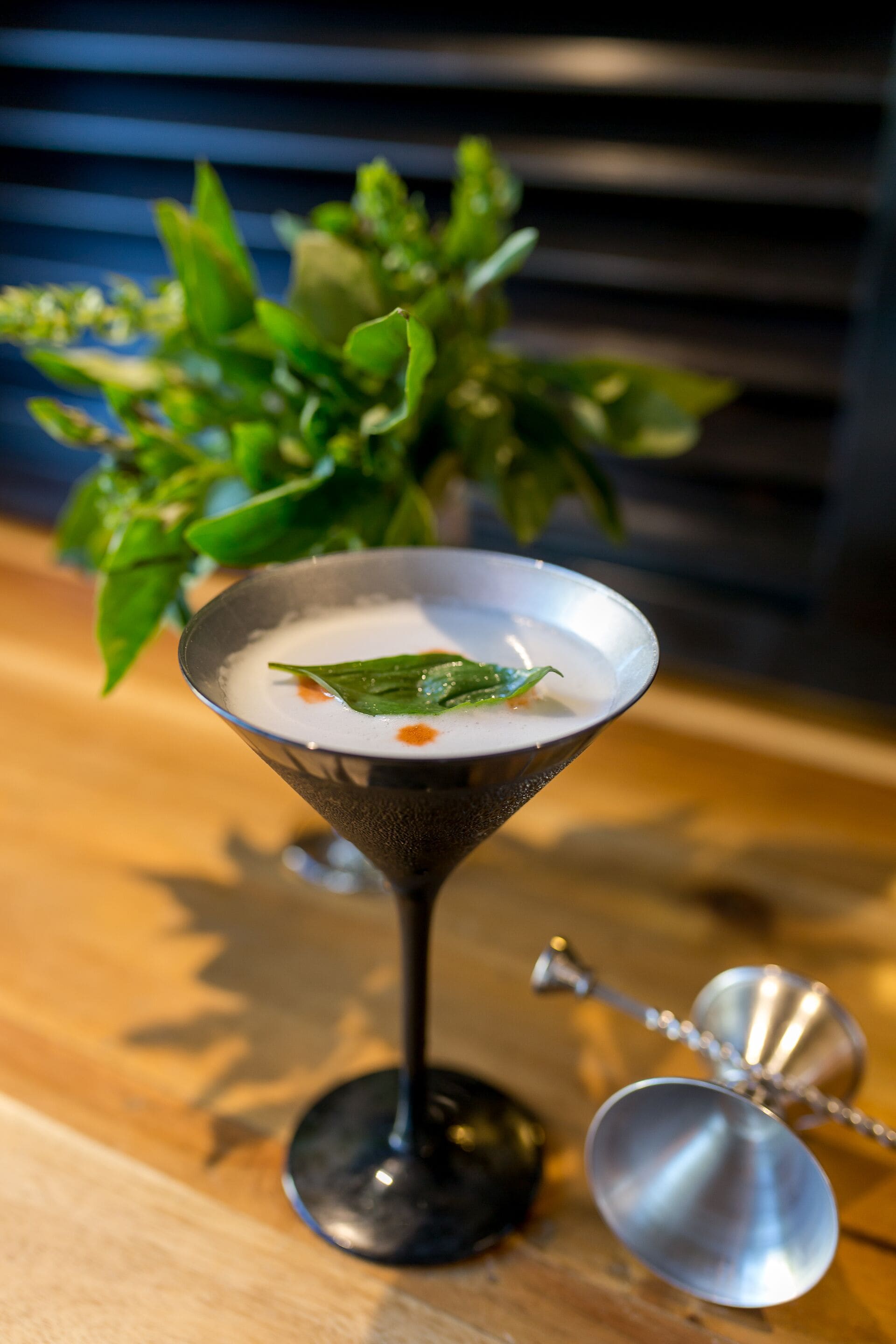 Um copo de martini com um enfeite sobre uma mesa de madeira.